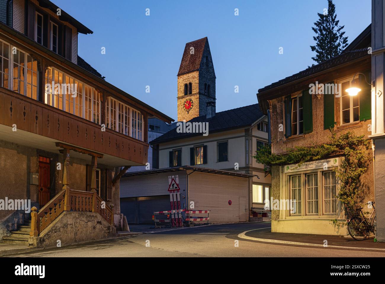 A calm evening scene with a church tower and warmly lit buildings, city ...