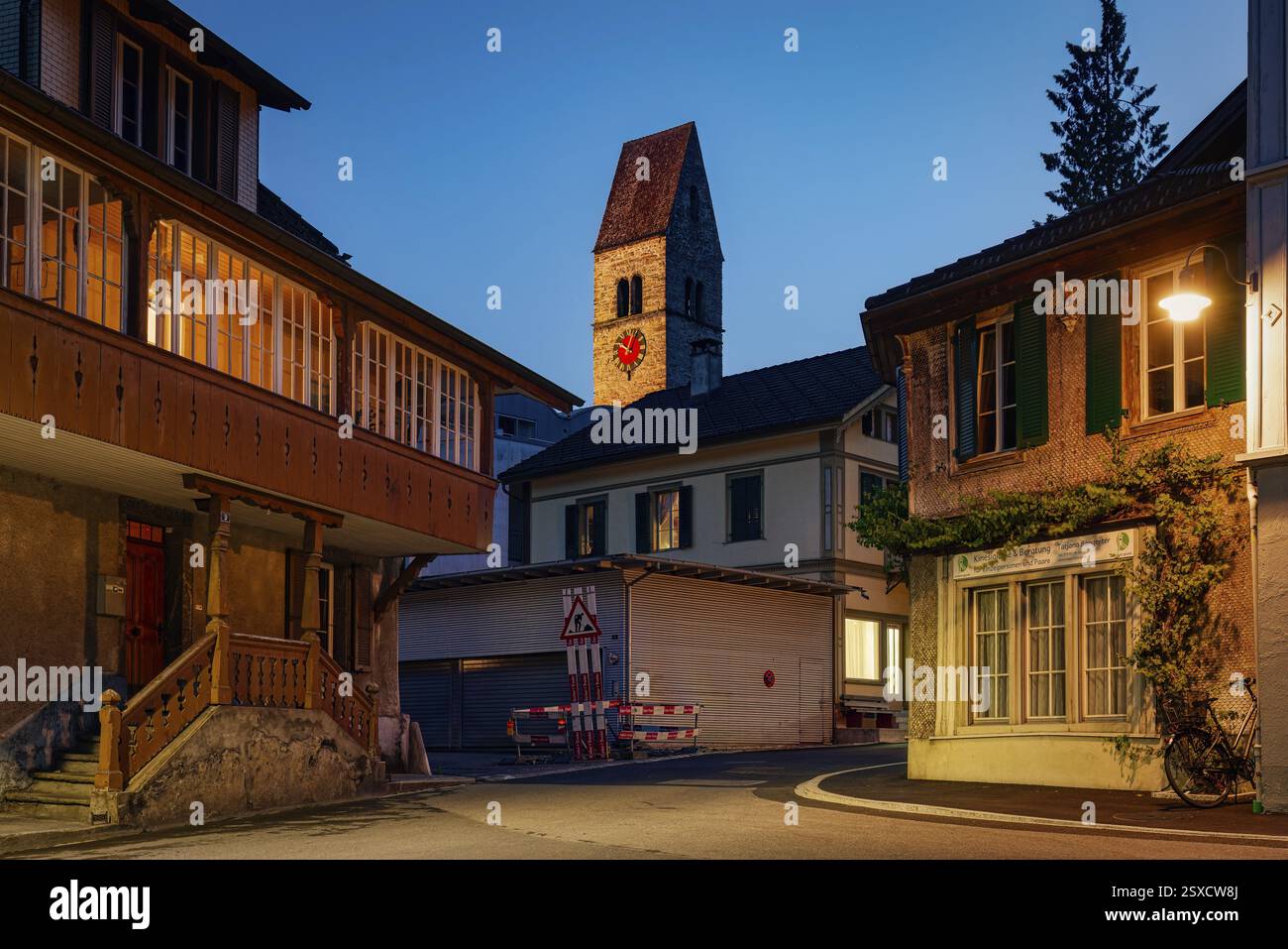 Quiet alley at night with a church tower and warmly lit buildings, city ...