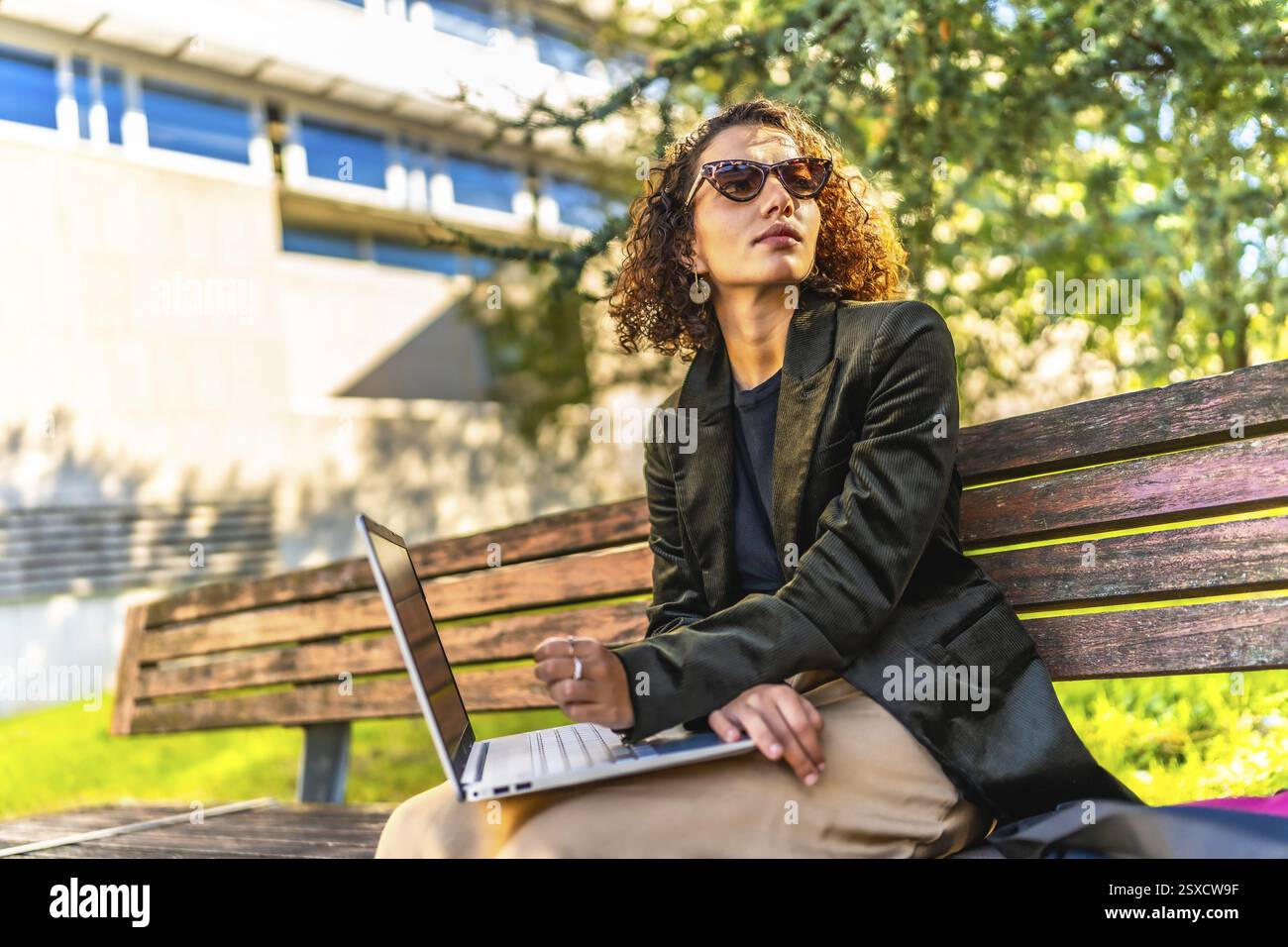Modern arab businesswoman using laptop sitting on park bench working on ...