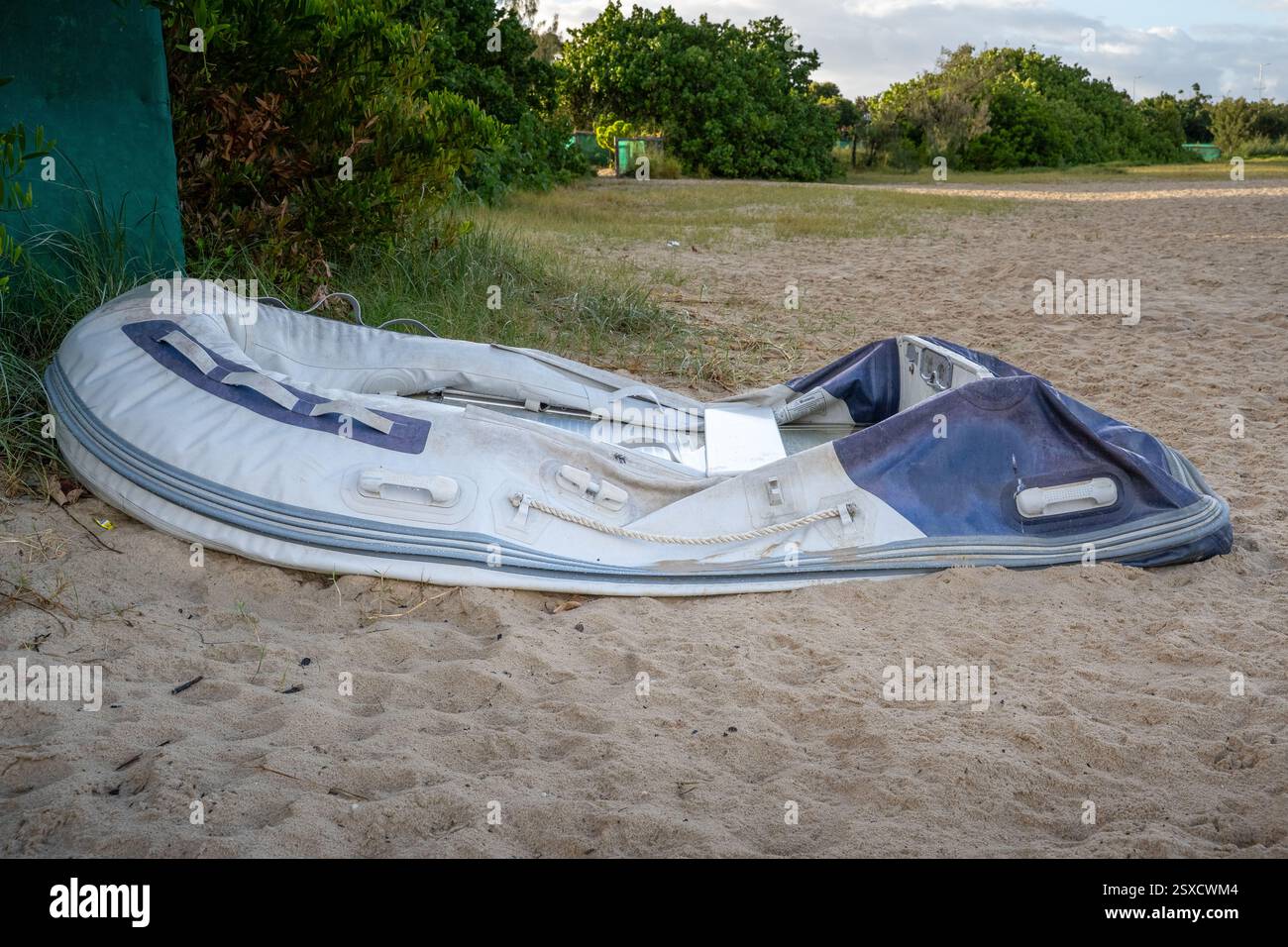 An abandoned inflatable boat sits on the beach somewhat deflated Stock ...
