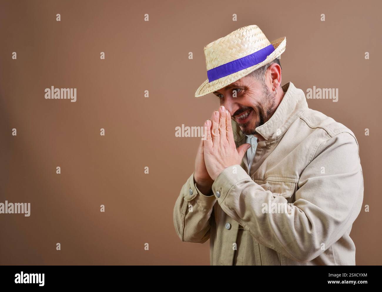 Cunning male tourist wearing casual clothes and a straw hat, rubbing ...