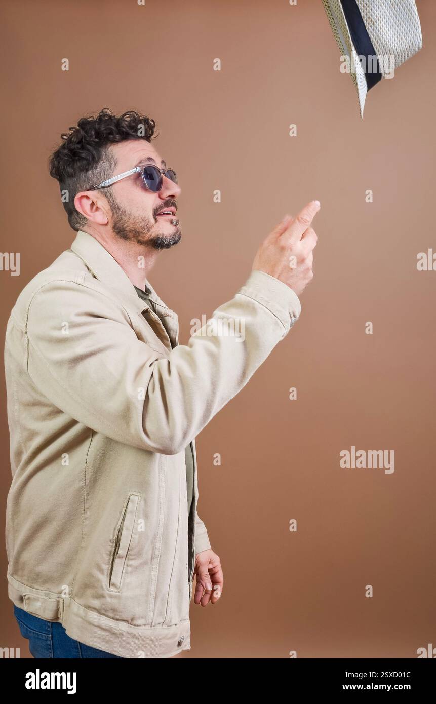 Side view of a stylish man wearing sunglasses pointing at his falling ...