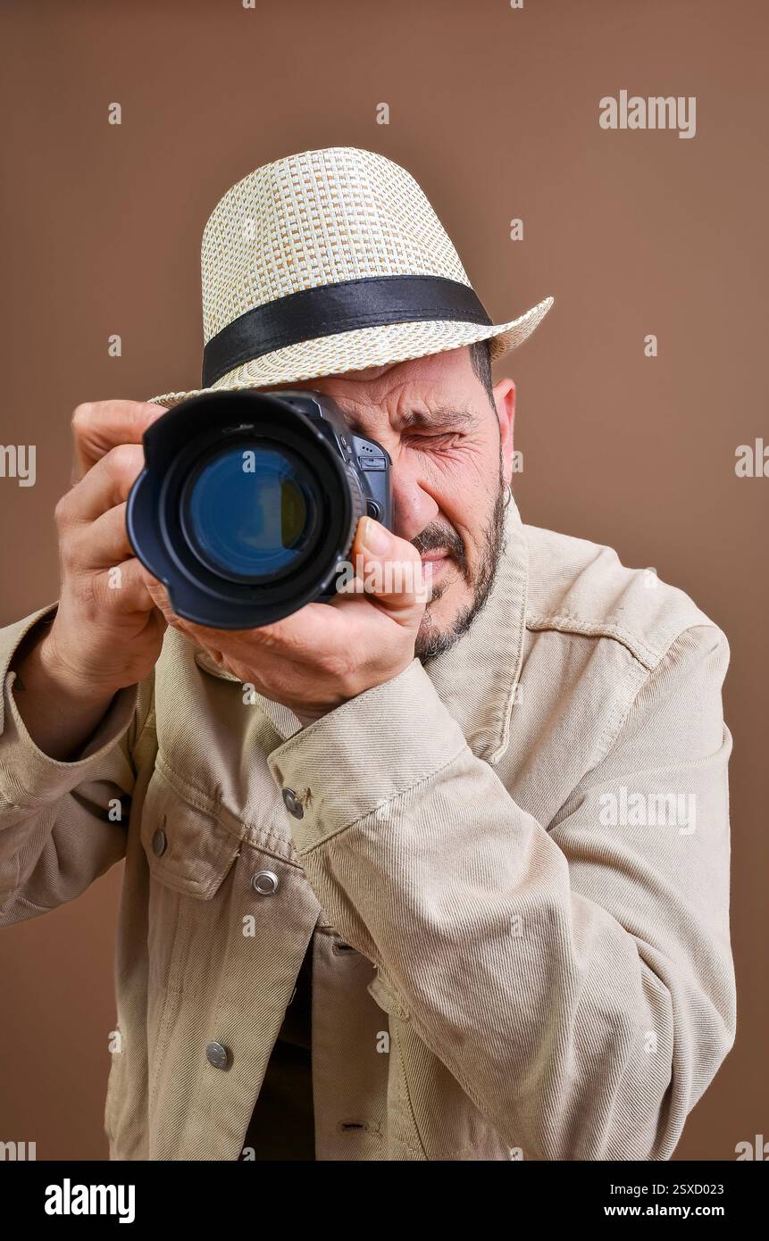 Photographer wearing straw hat and beige jacket framing a shot with ...