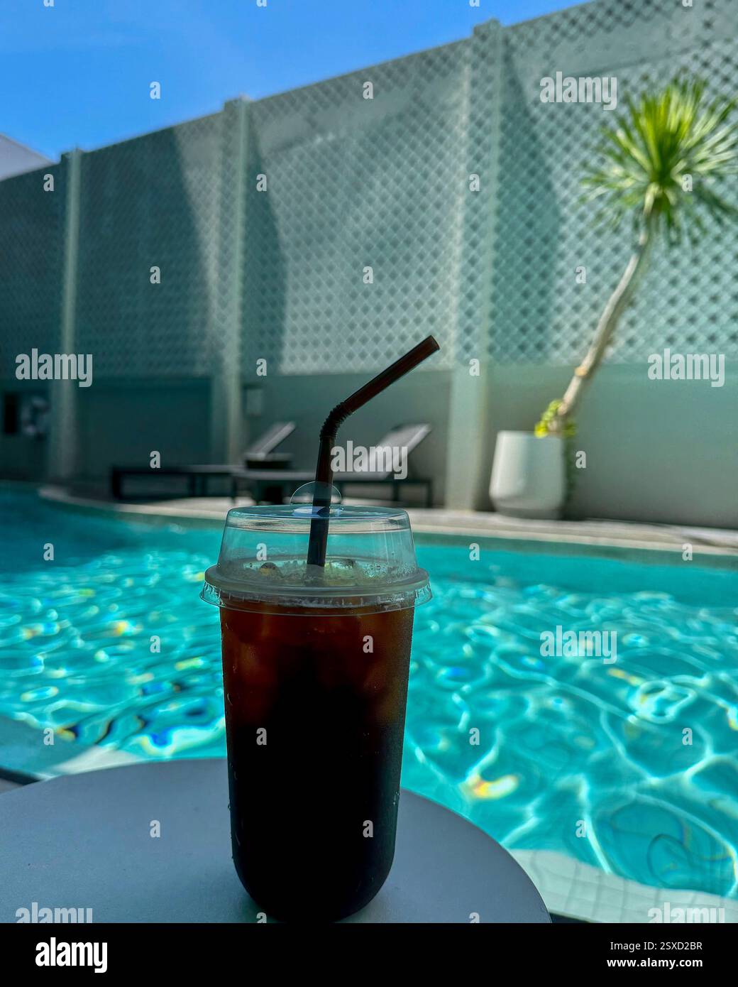 Iced Coffee by the Pool An iced coffee in a plastic cup with a straw ...