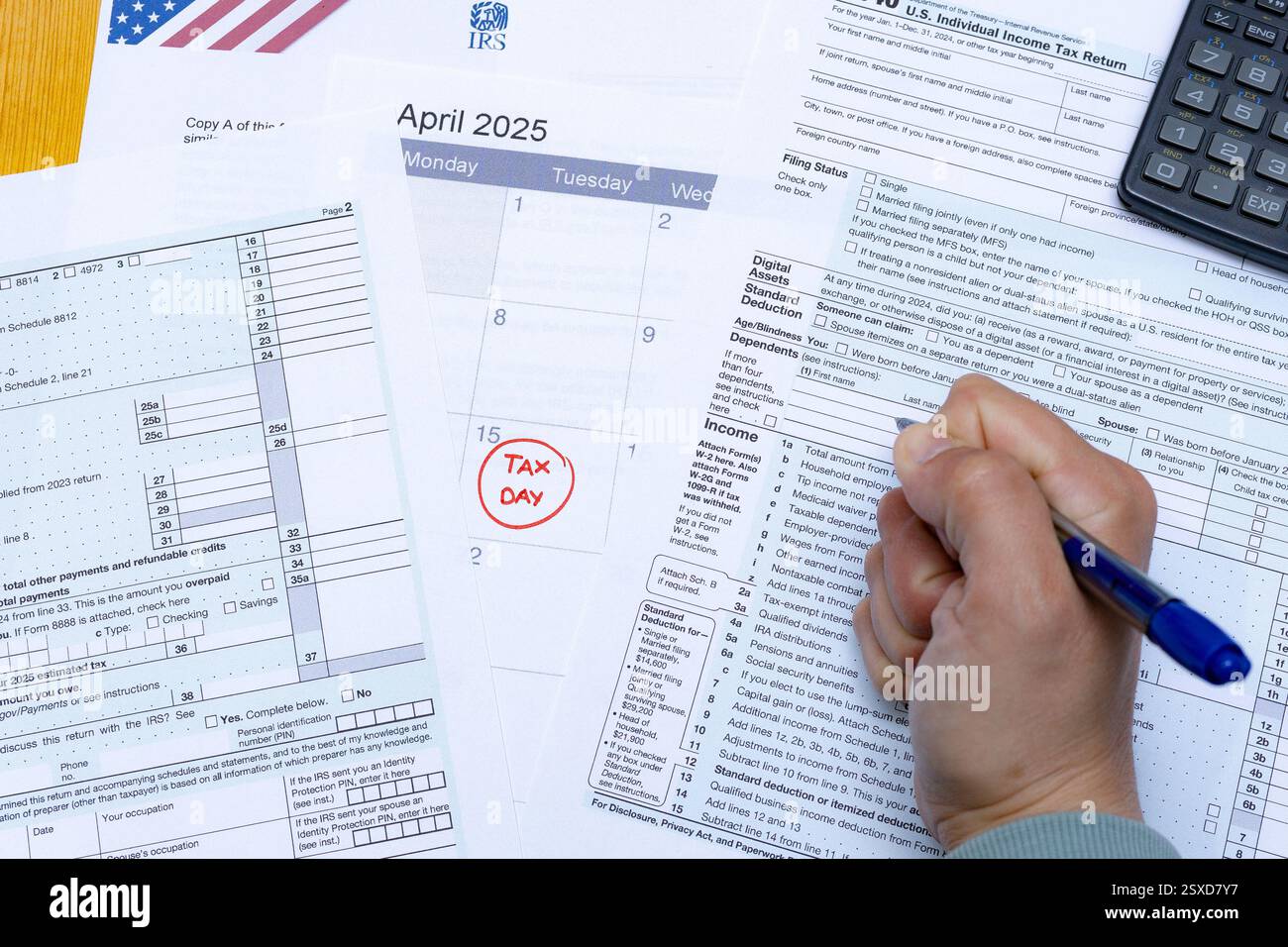 A close-up shot of a hand gripping a pen over IRS tax forms, with a ...