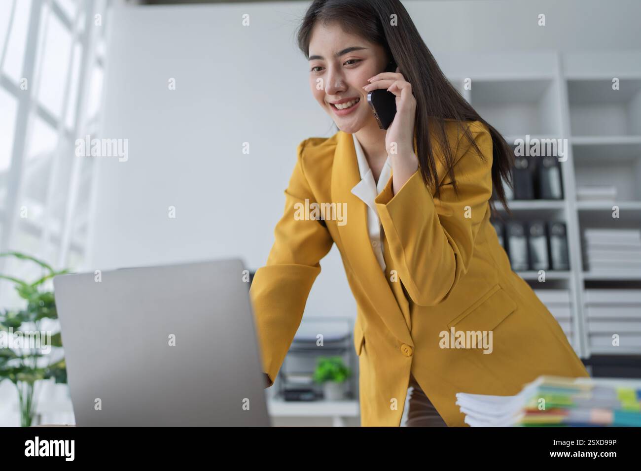 Young businesswoman in yellow blazer engaged in a phone call while ...