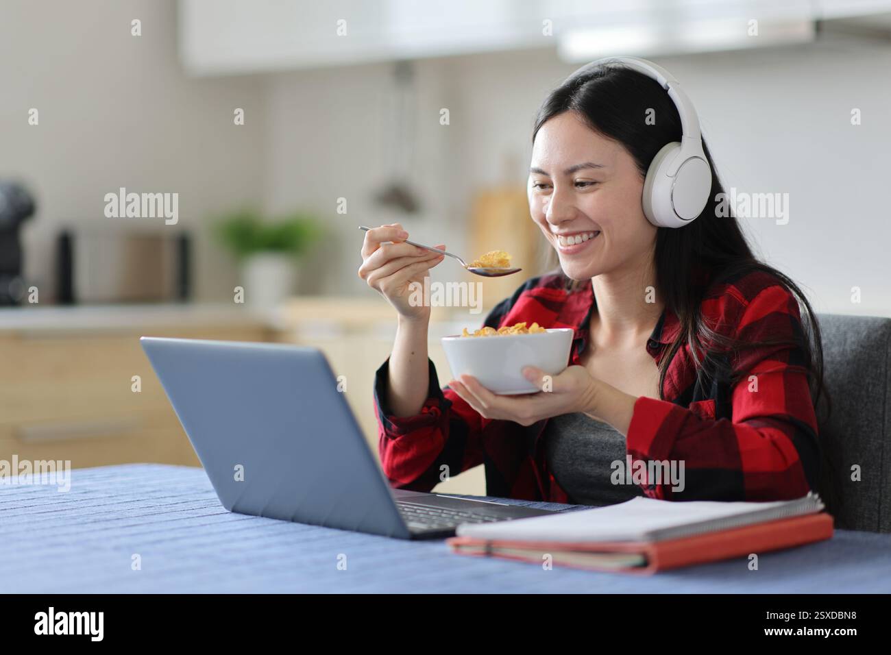 Happy asian student eating cereal while e-learning watching tutorial on ...