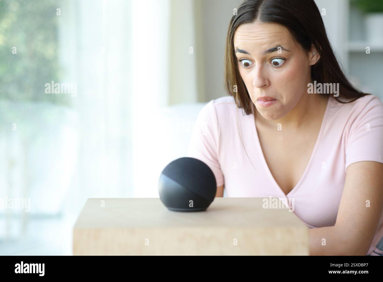 Perplexed woman looking at her smart speaker at home Stock Photo - Alamy