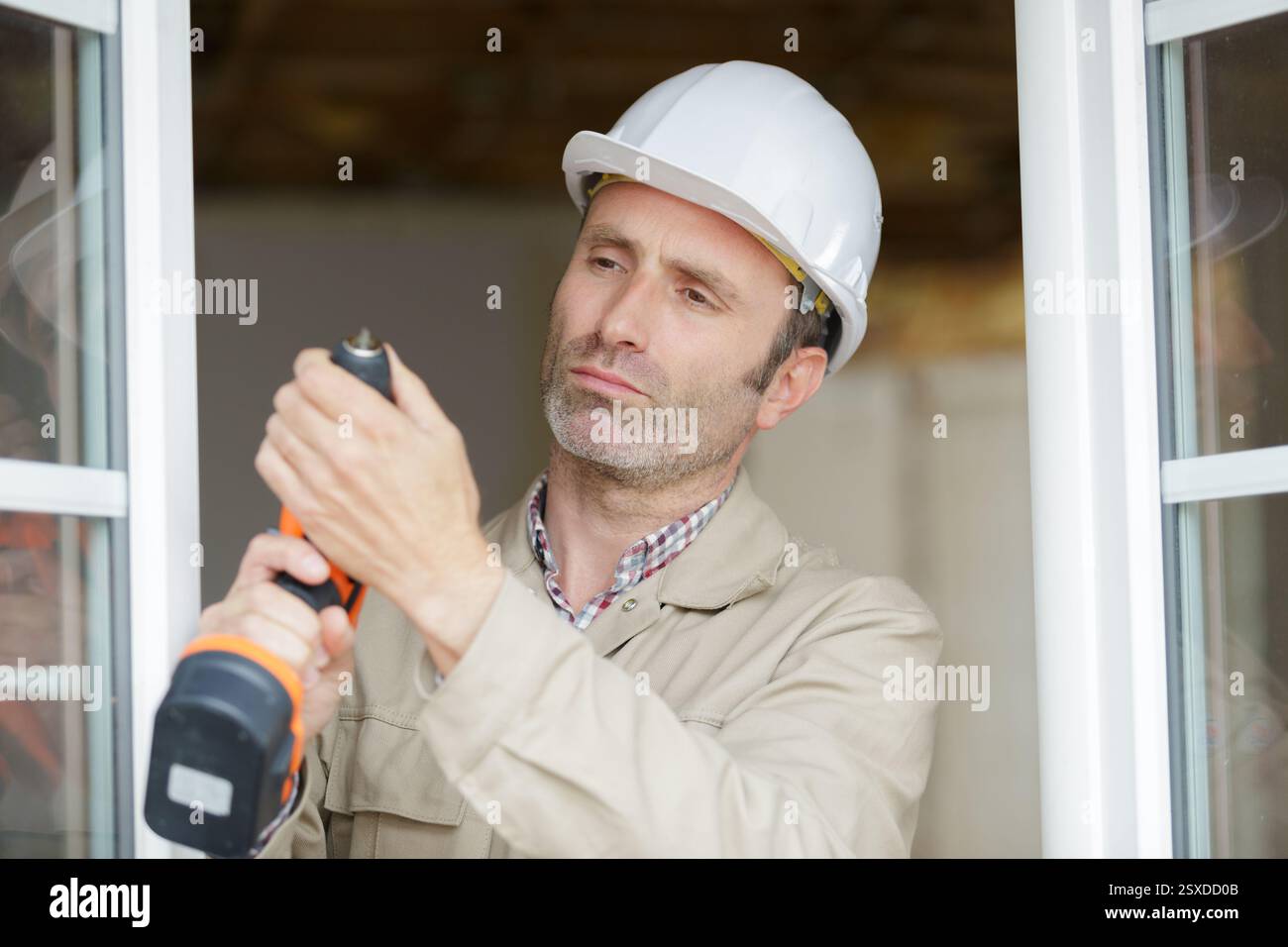 man drilling a hole in a window frame Stock Photo - Alamy