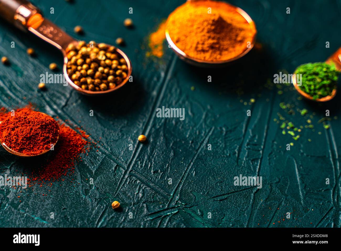 Spices in copper measuring spoons on a malachite textured background ...