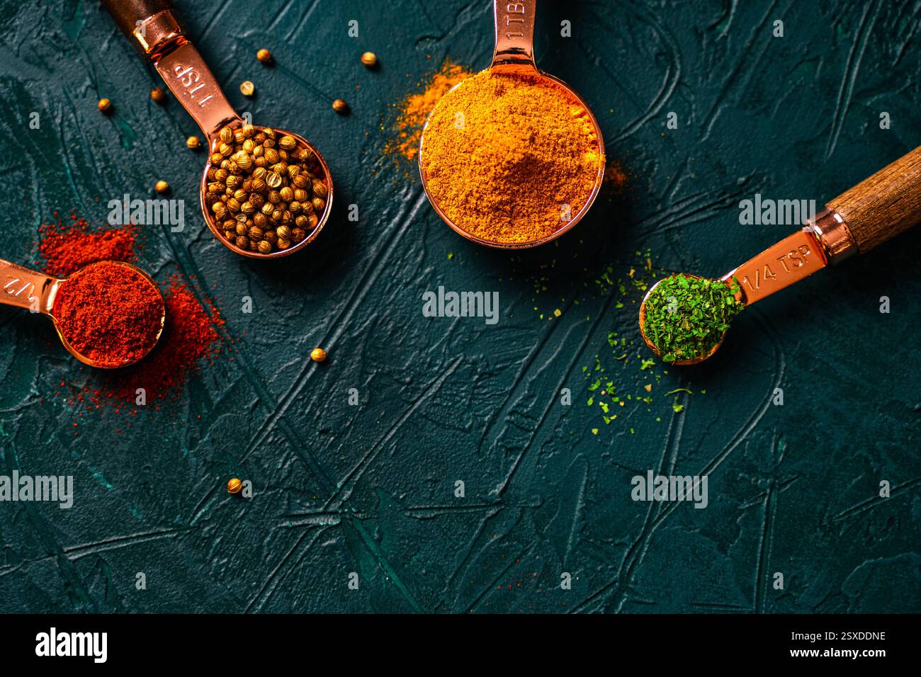 Spices in copper measuring spoons on a malachite textured background ...