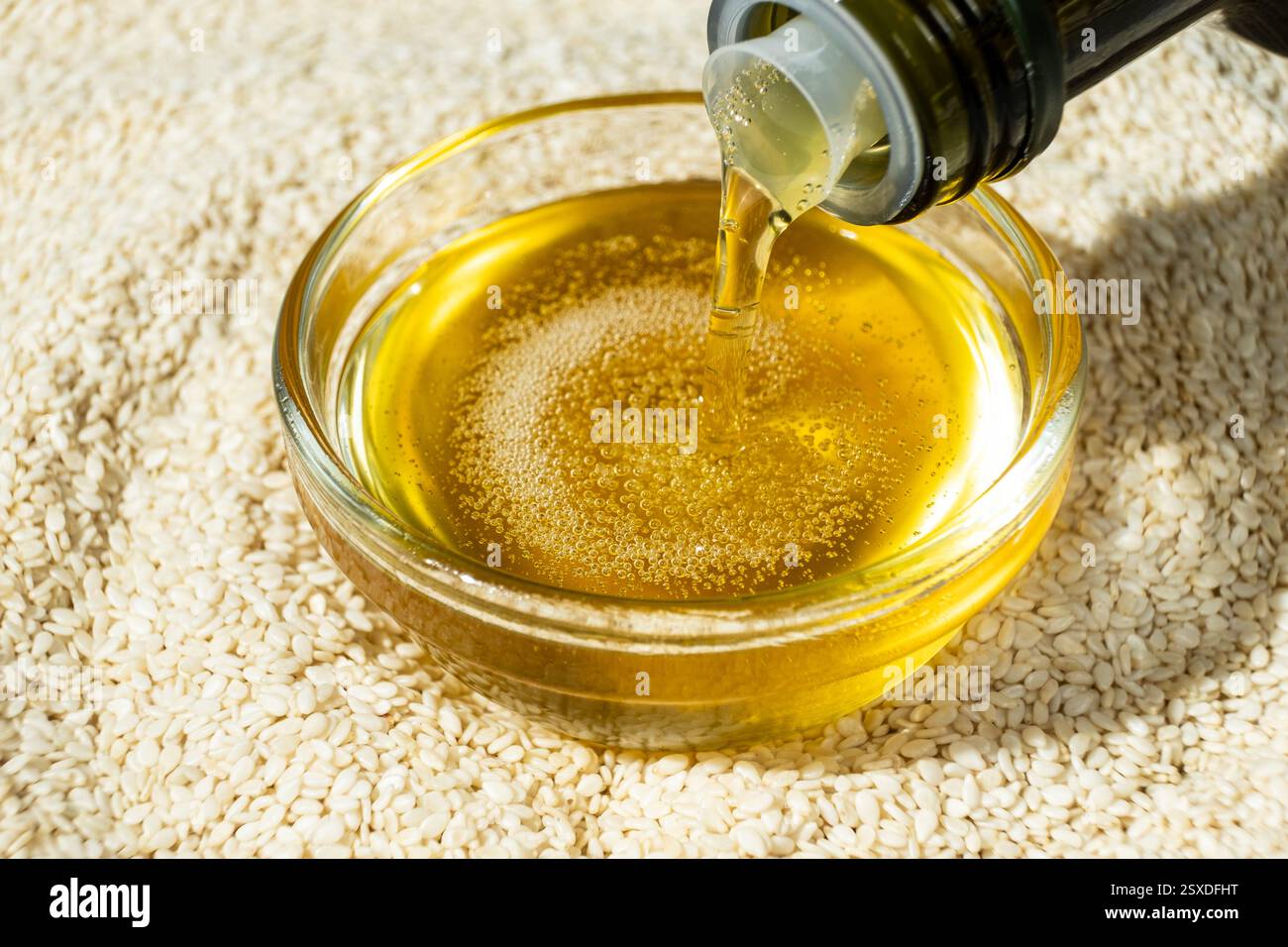 Unrefined sesame oil pouring out of bottle Stock Photo - Alamy