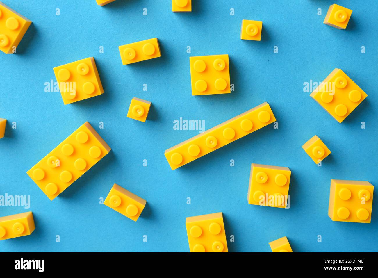 Constructor toy. Many yellow building blocks on light blue background ...