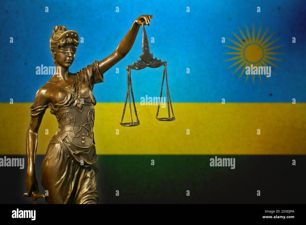 Close-up of a small bronze statuette of Lady Justice before a flag of ...