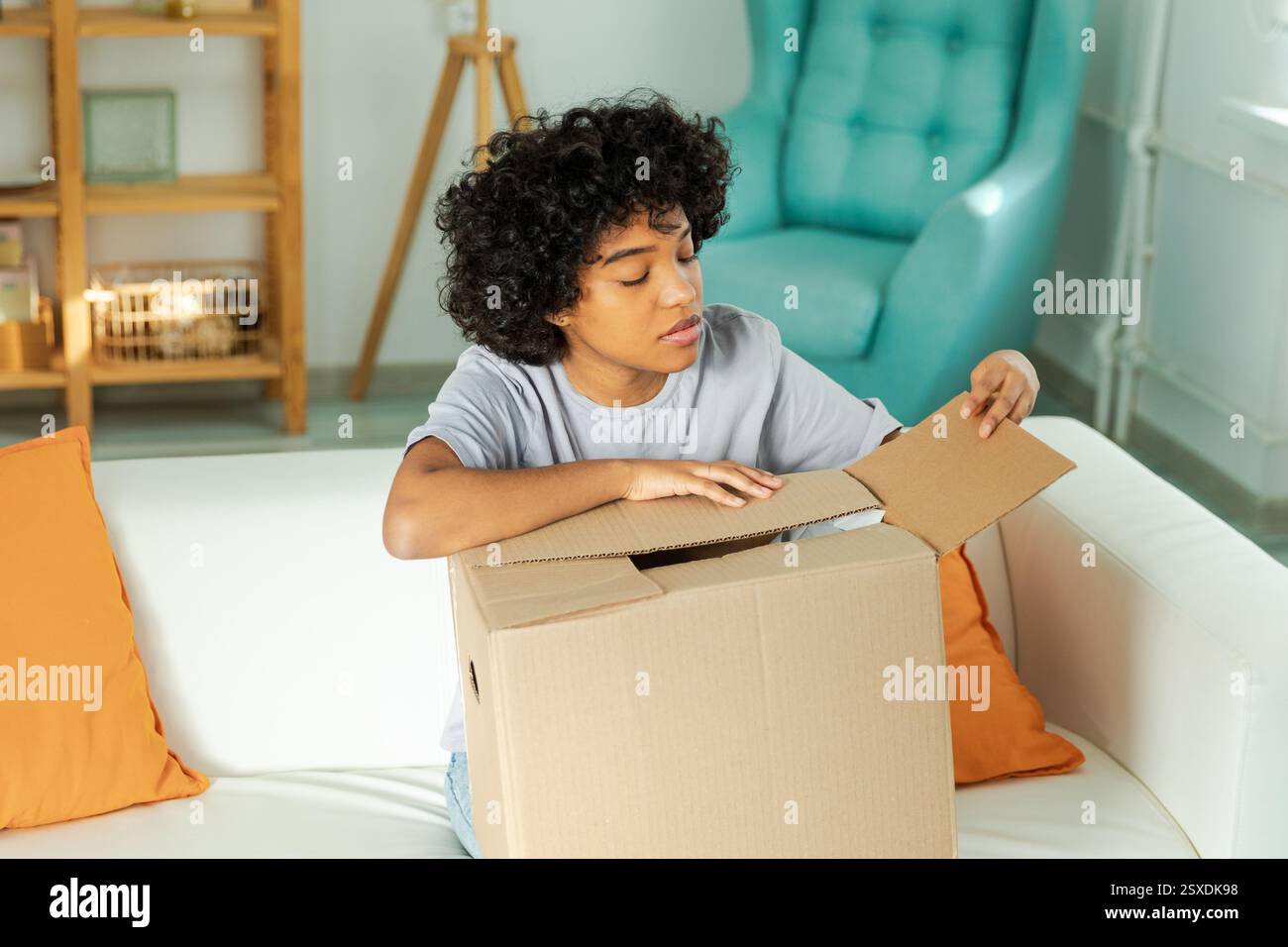 African girl unpacking delivery looking in box. Happy woman opening ...