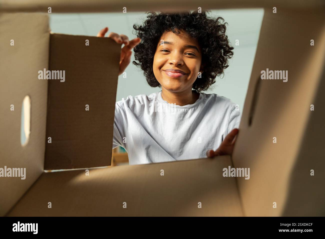 Inside of cardbox bottom view. African girl unpacking delivery looking ...