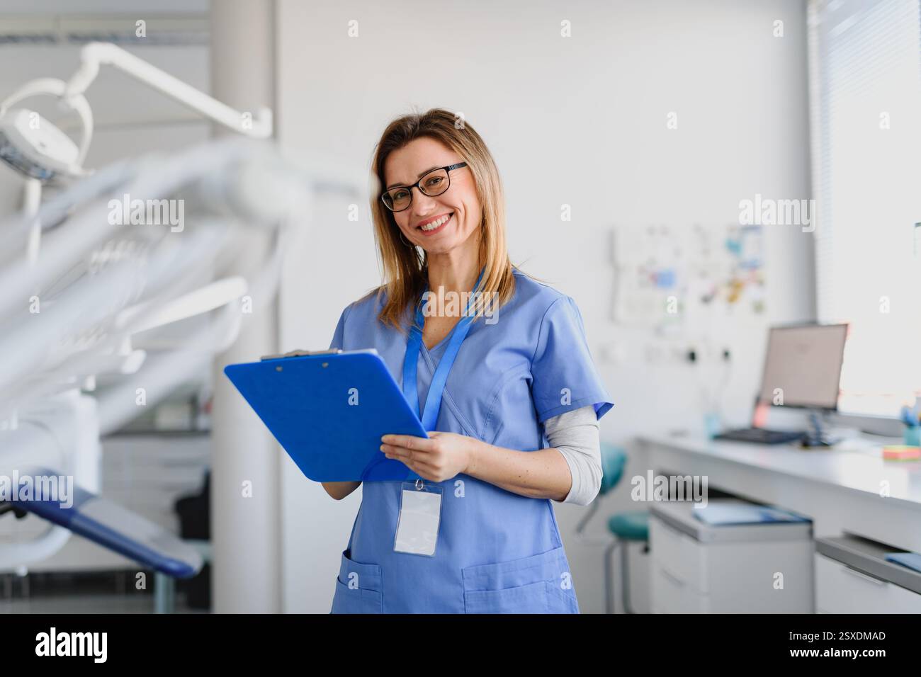 Friendly nurse writing notes in patients records, standing a modern ...