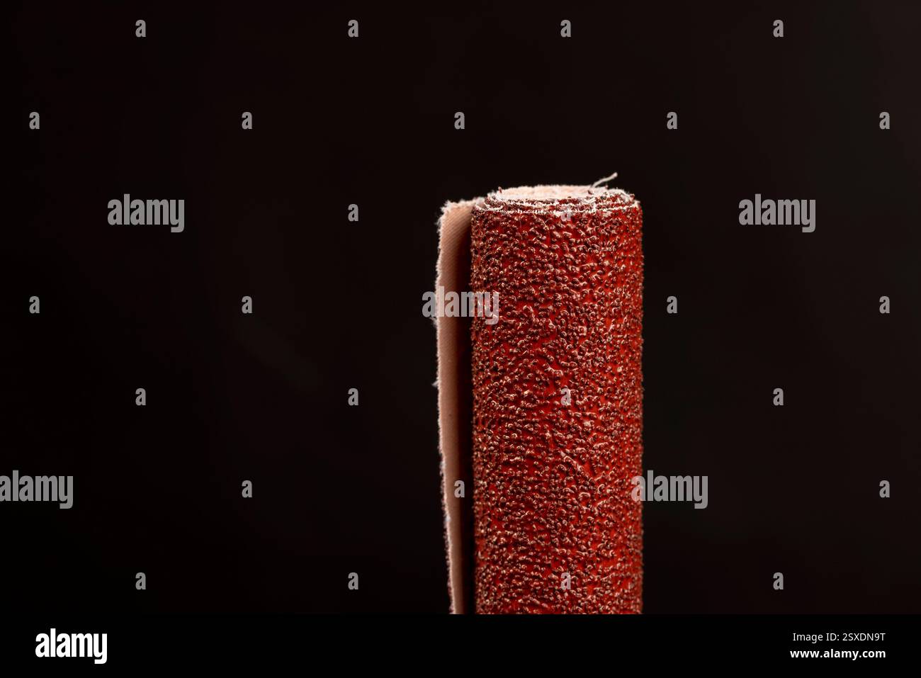 red sandpaper for working with wood and metal rolled into a tube on a ...
