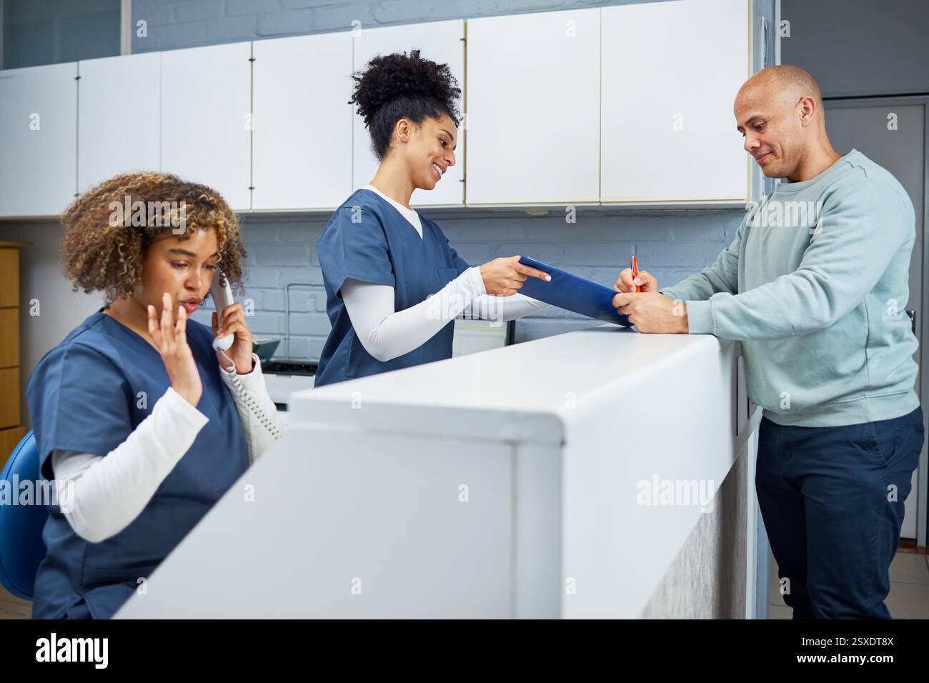 Receptionists Assisting Patient in a Modern Medical Office Environment ...