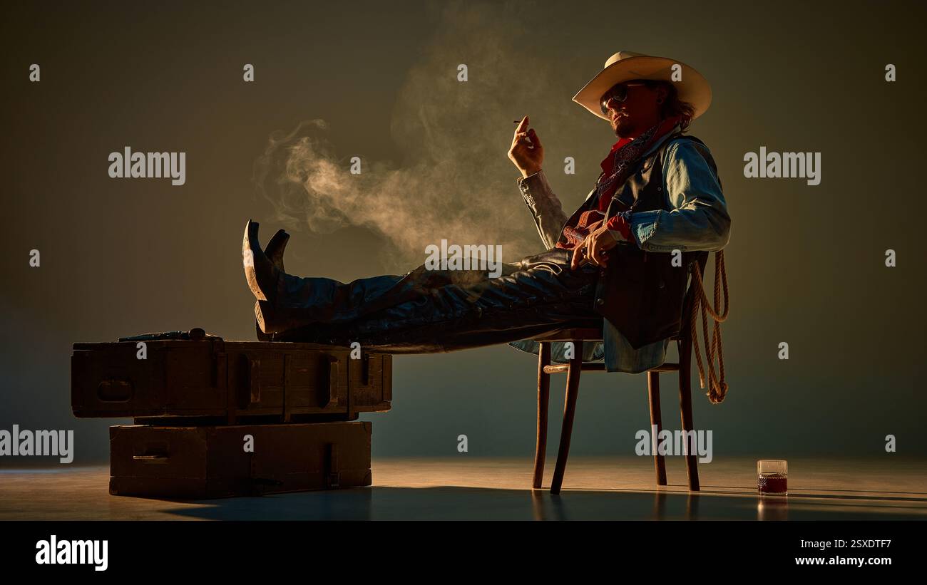 Handsome, brutal man, western cowboy sitting on chair, wearing hat ...