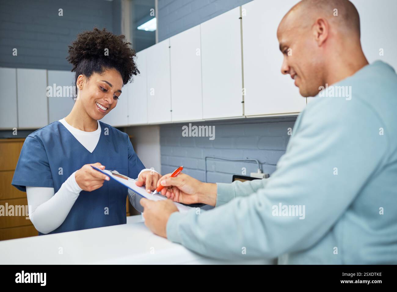 Smiling Healthcare Professional Assisting Patient with Forms at ...