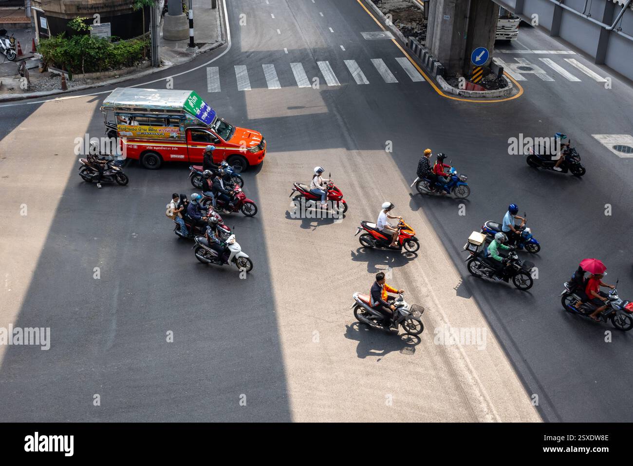 A view of an intersection with a truck and motorcycles in shadow and ...