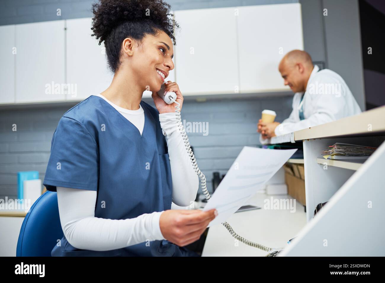 Healthcare Receptionist in Uniform Communicating on Telephone at ...