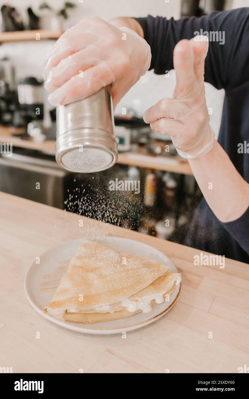 Barista dusting powdered sugar on a crepe in a modern cafe Stock Photo ...
