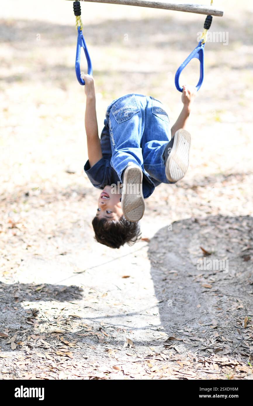 Child hanging upside-down on playground rings, smiling playfully Stock ...