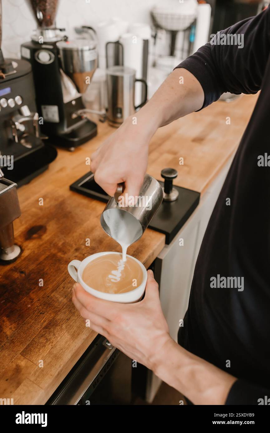 Barista pouring steamed milk into coffee cup creating latte art Stock Photo - Alamy