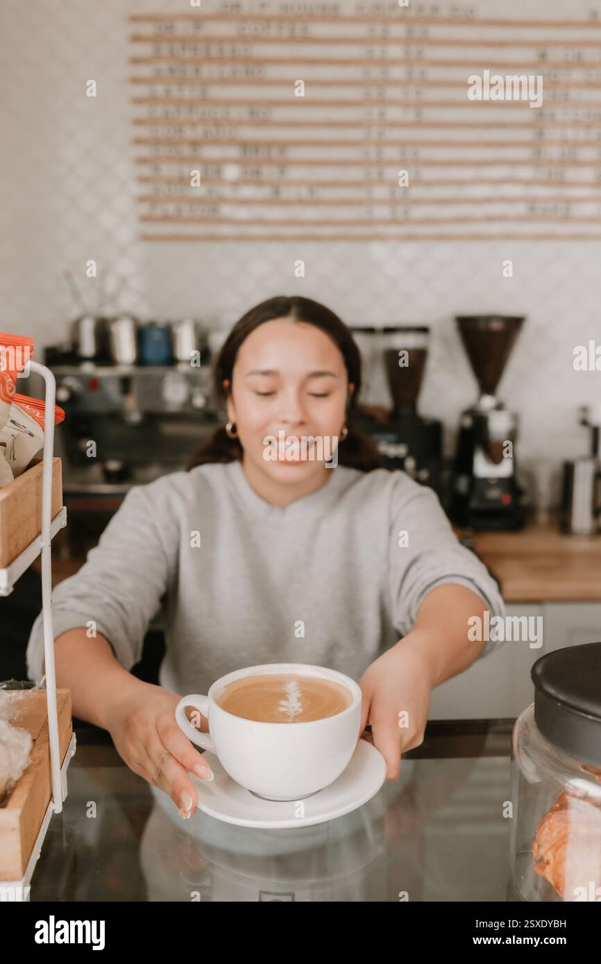 Barista serving a latte with leaf latte art in a modern coffee shop ...