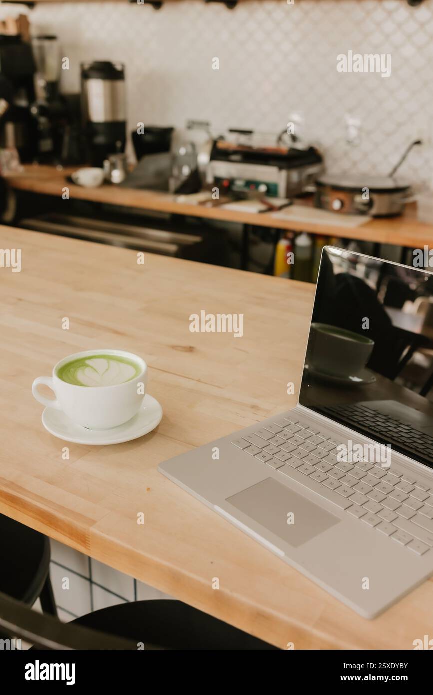 Matcha latte and open laptop on wooden cafe counter Stock Photo - Alamy