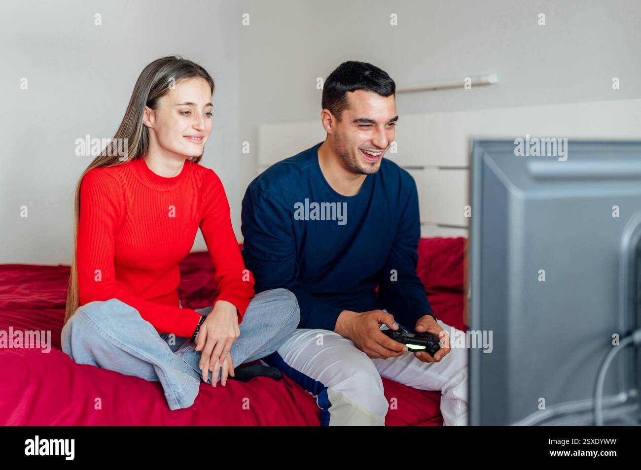 Young couple playing video games in bed using wireless controller Stock ...