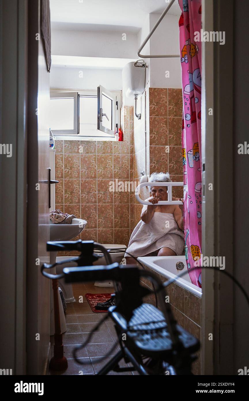 Elderly disabled woman sits in a bathroom wrapped in a towel after ...