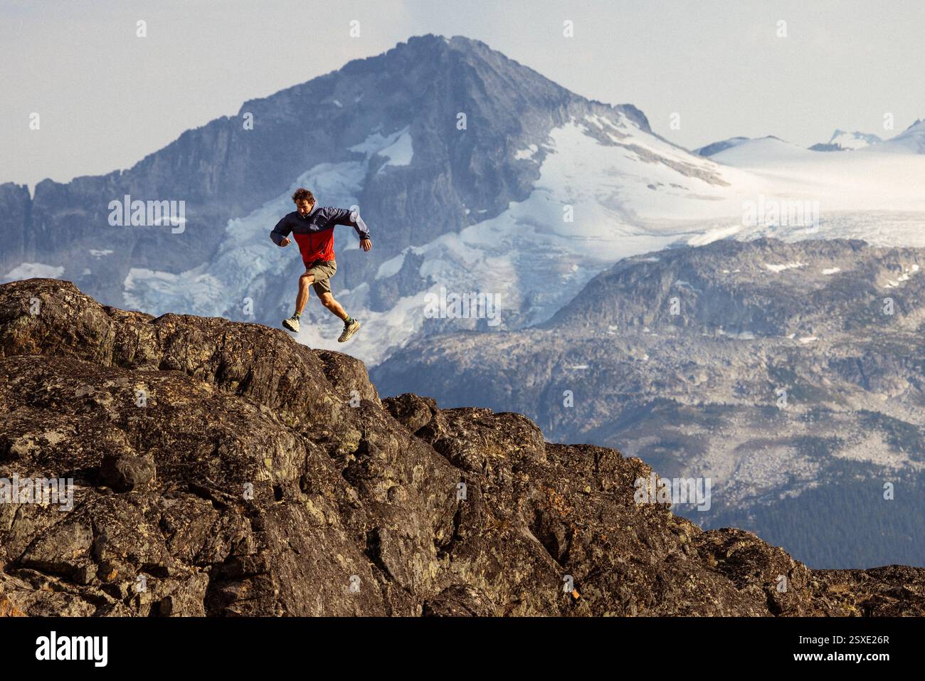 Trail runner running over rugged terrain with glaciers and mountains ...
