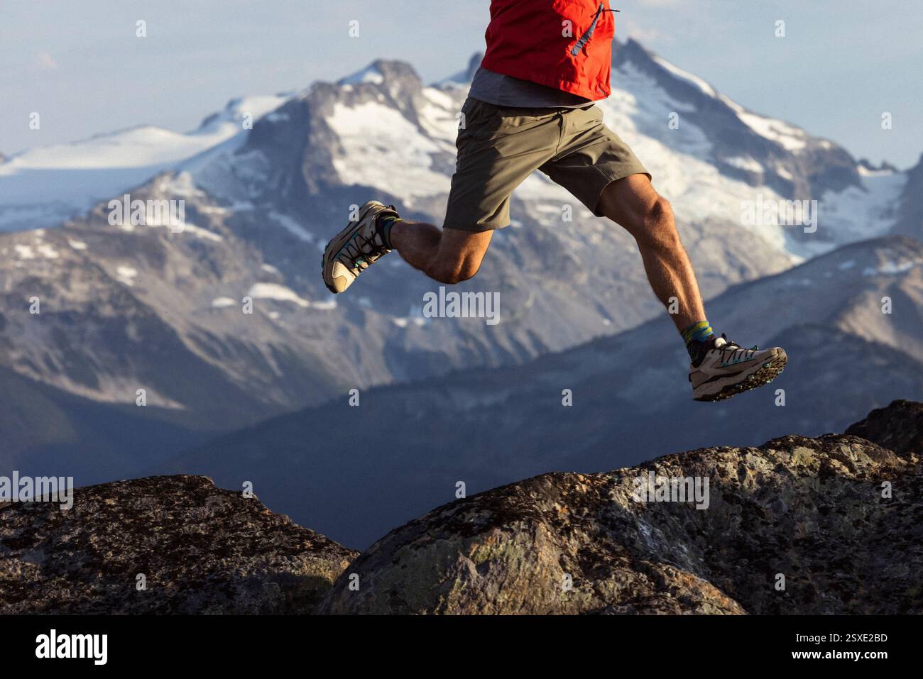 Trail runner soaring over rugged terrain with glaciers in view Stock ...