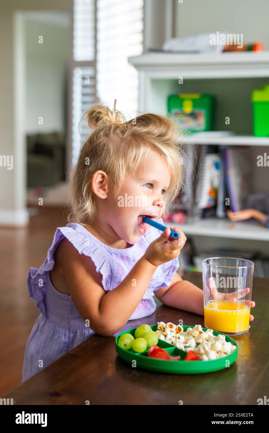 Toddler Girl Eating Snack and Drinking Orange Juice at the Table Stock ...
