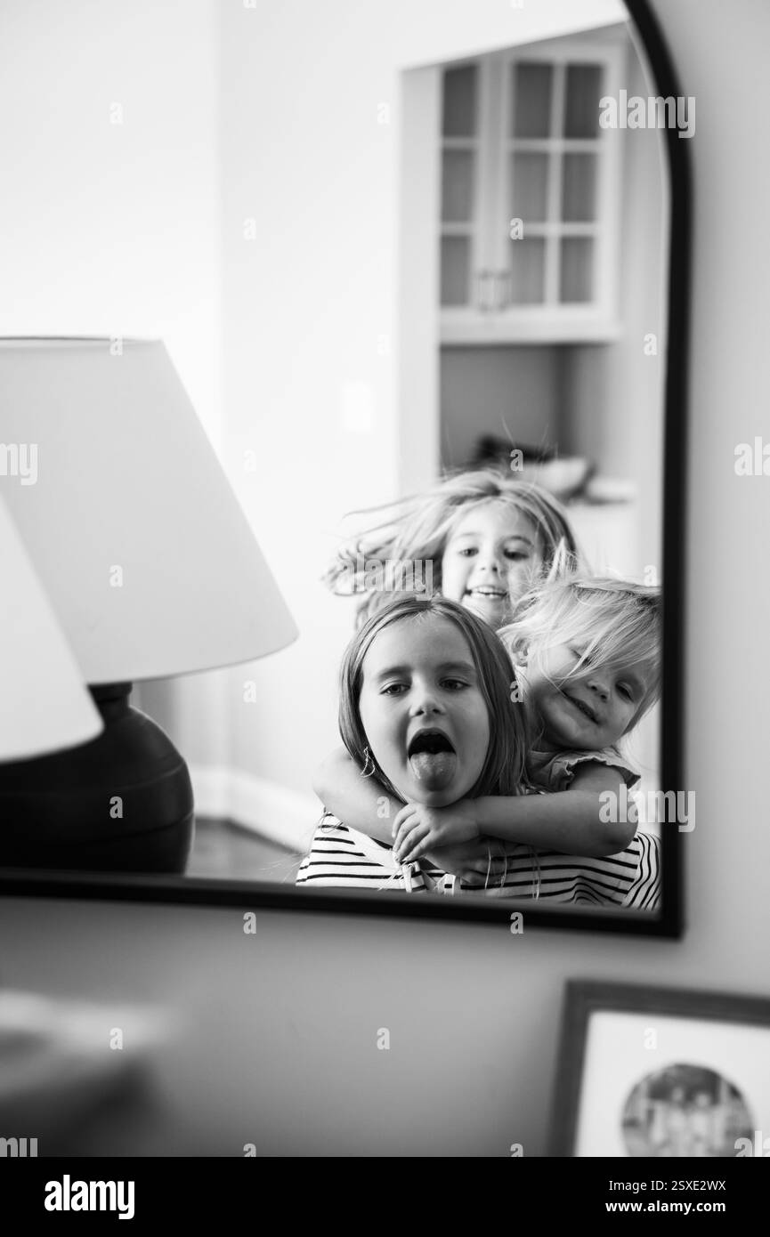 Sisters Hugging while Making Faces in the Living Room Mirror Stock ...