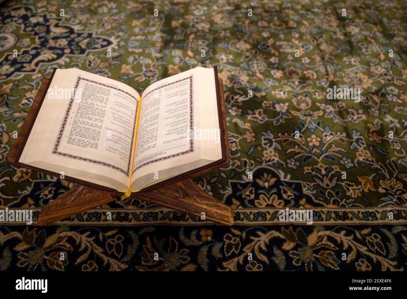 An opened holy book of the Quran on a green carpet at the Prophet ...