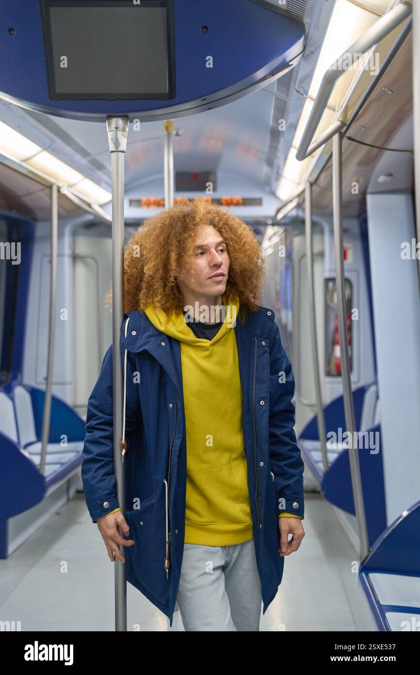 Stylish student traveling alone on a metro train, standing inside the ...