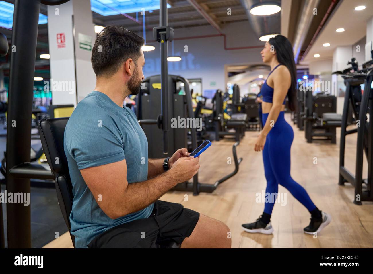 Two individuals focused on their fitness routine in a modern gym ...