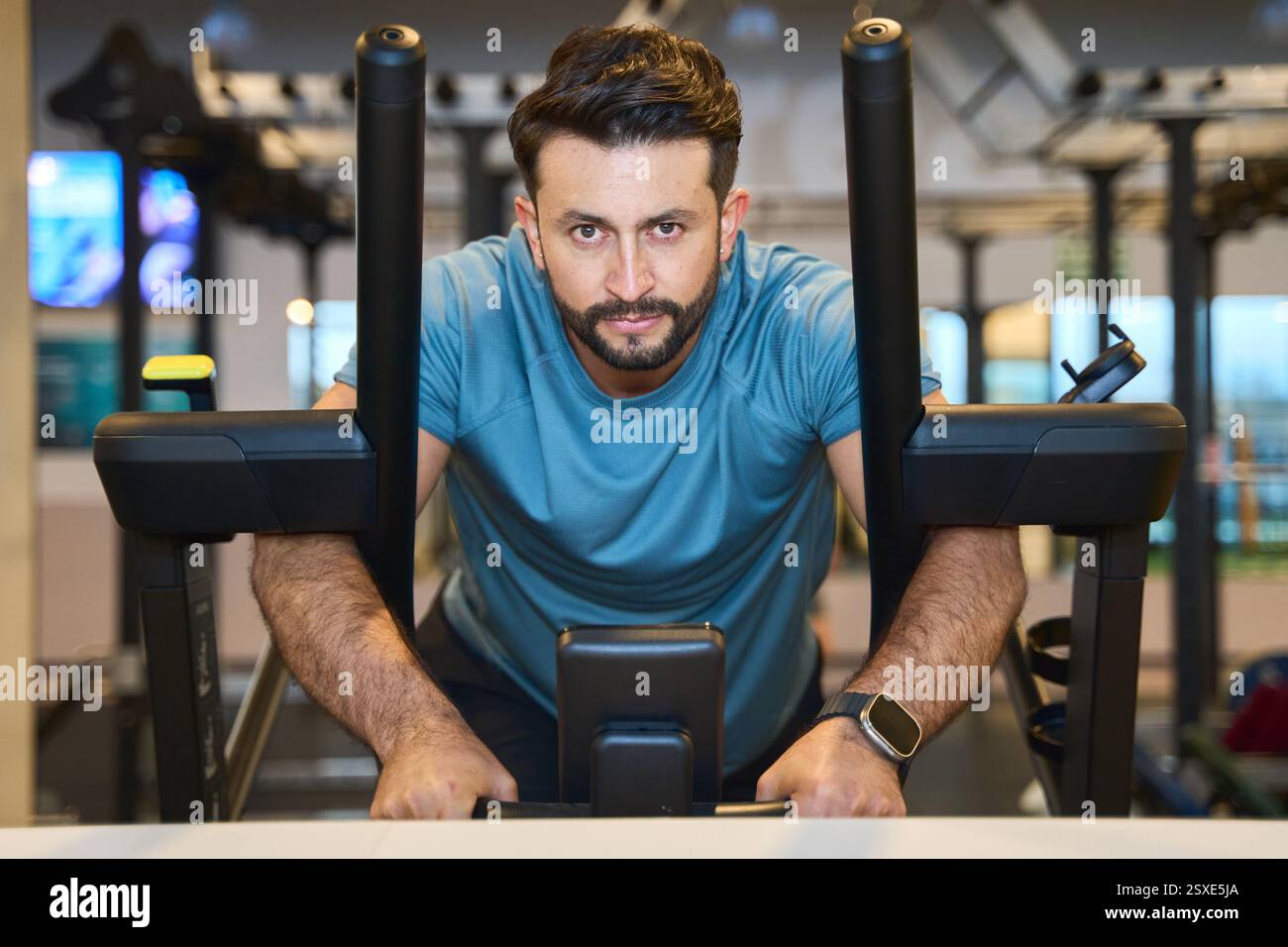 Man intensely working out on an elliptical trainer in a modern gym ...