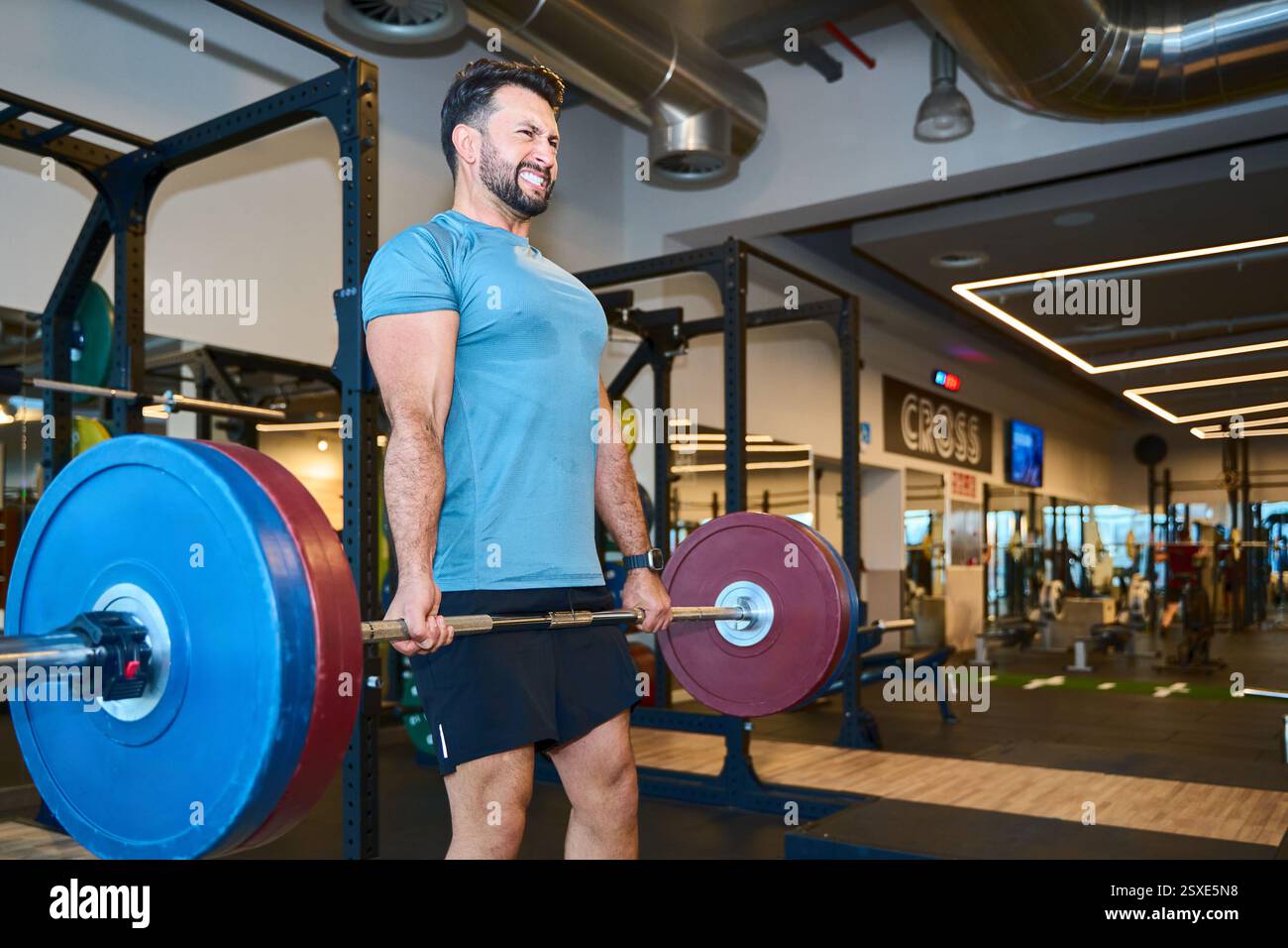 Man performing a deadlift with a barbell in a well equipped gym ...