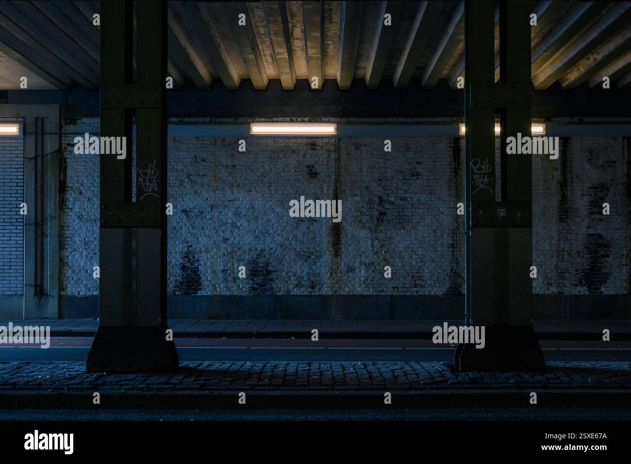 A moody urban underpass with steel beams and textured brick walls ...