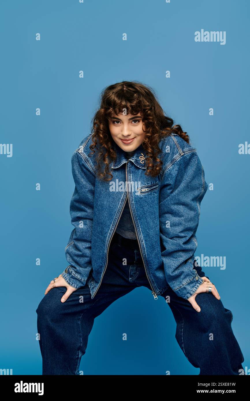 Emotional woman in trendy denim outfit poses playfully against a bright ...