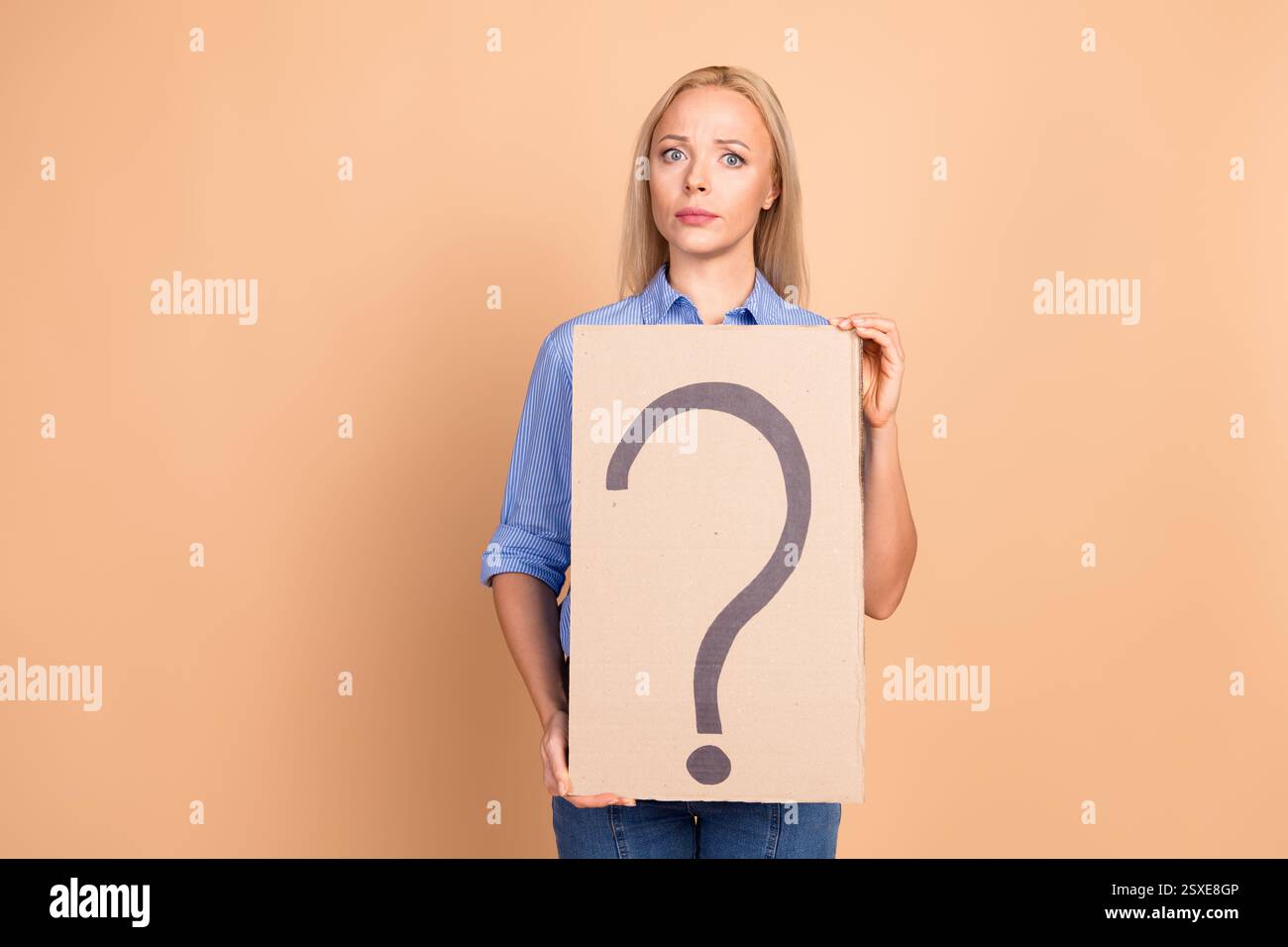 Young professional woman holding a question mark cardboard sign against ...