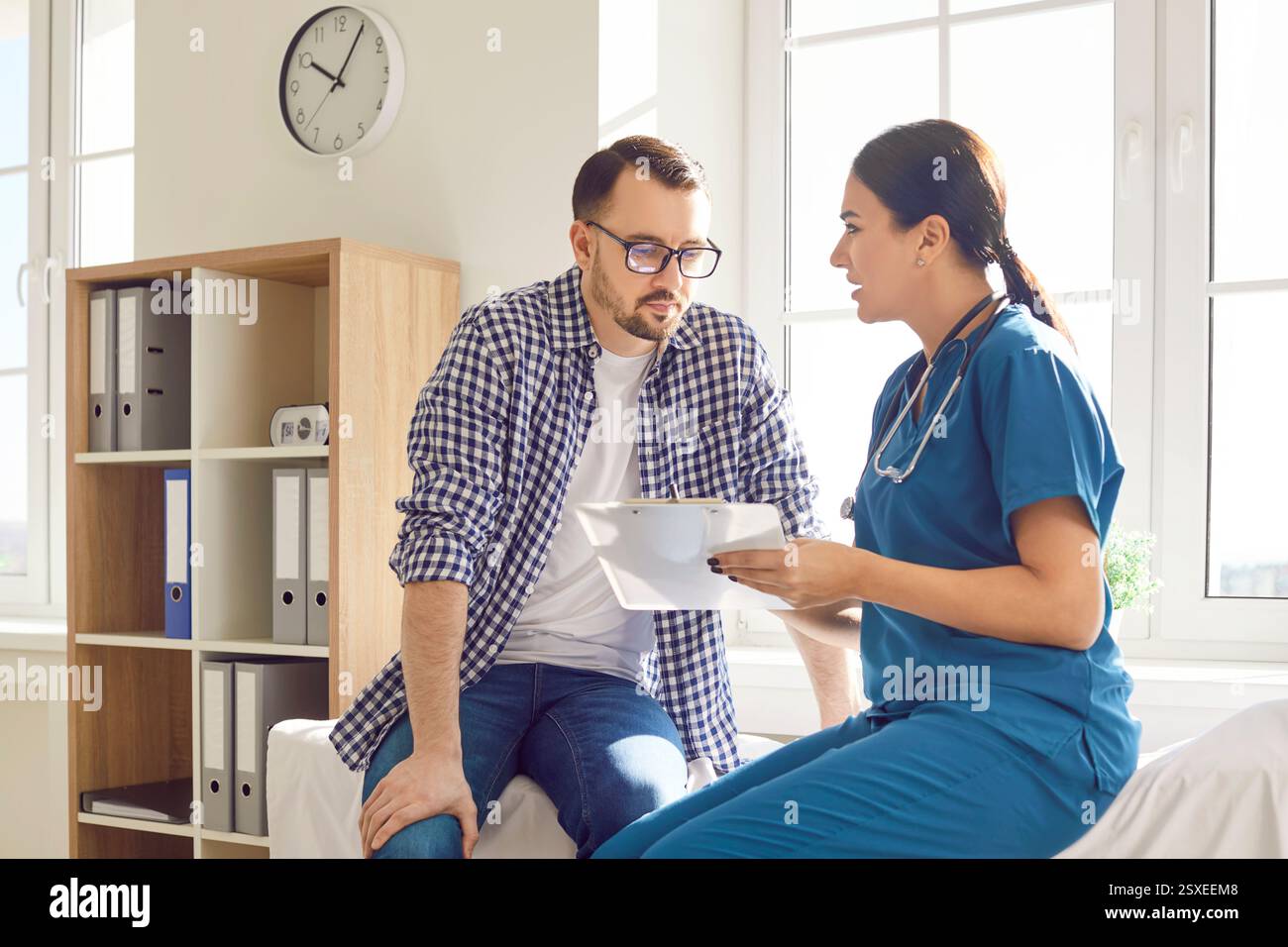 Female Doctor Engages Conversation with Male Patient Stock Photo - Alamy