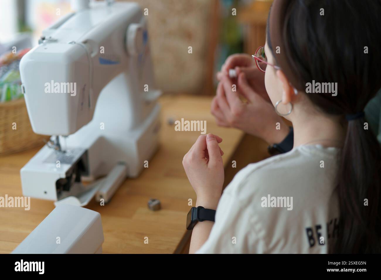 A mother shows her daughter how to thread a sewing machine and sew ...