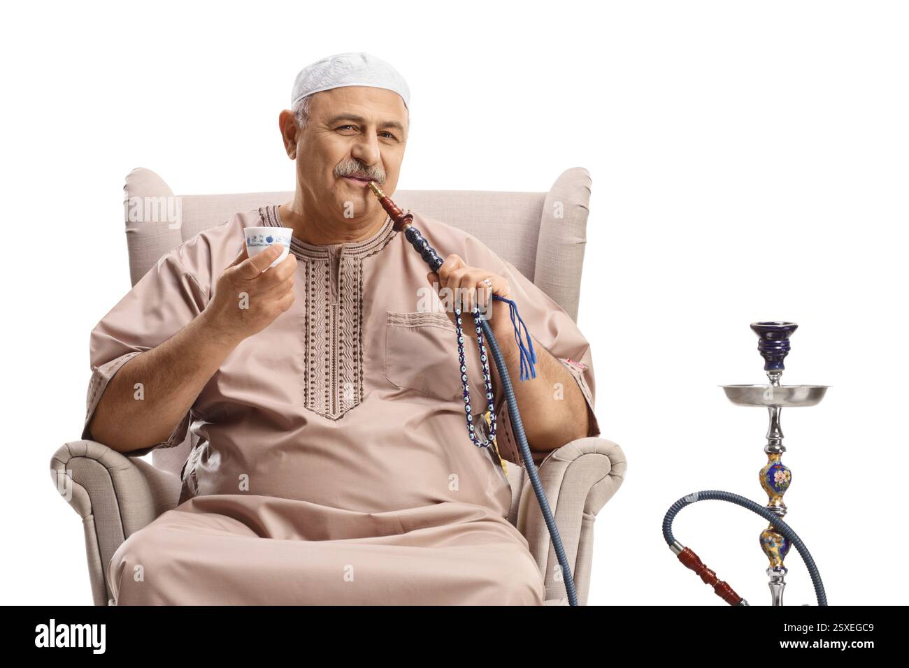 Man in ethnic clothes sitting in an armchair and smoking shisha ...