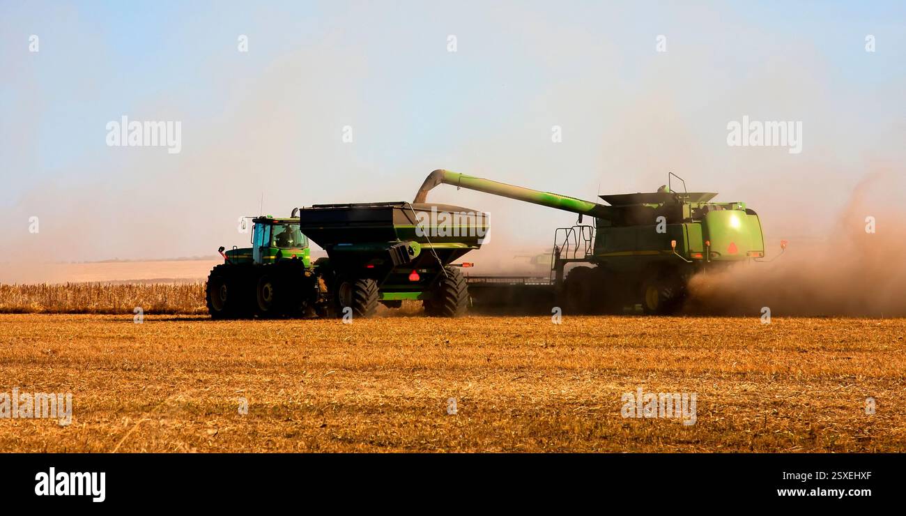 Green tractor is pulling a green combine harvester. The combine ...